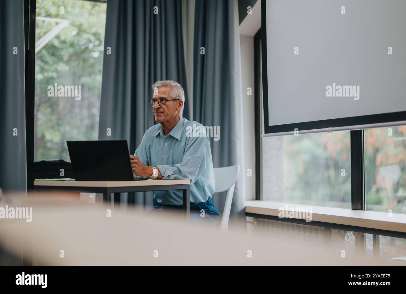 Senior teacher conducting class in a cozy modern classroom Stock Photo ...