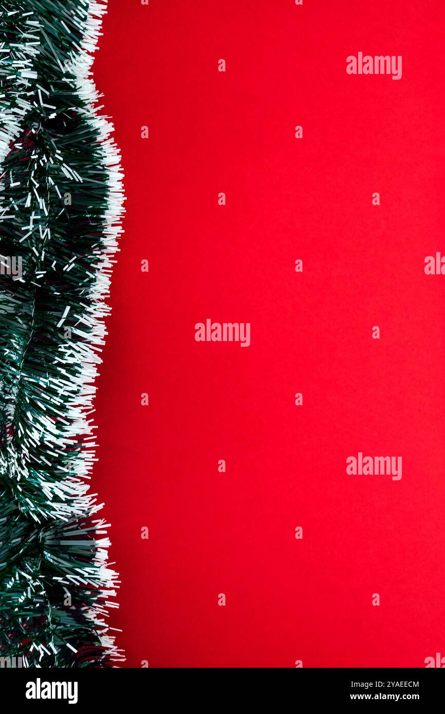 A red background with a green Christmas garland on the left side and a ...