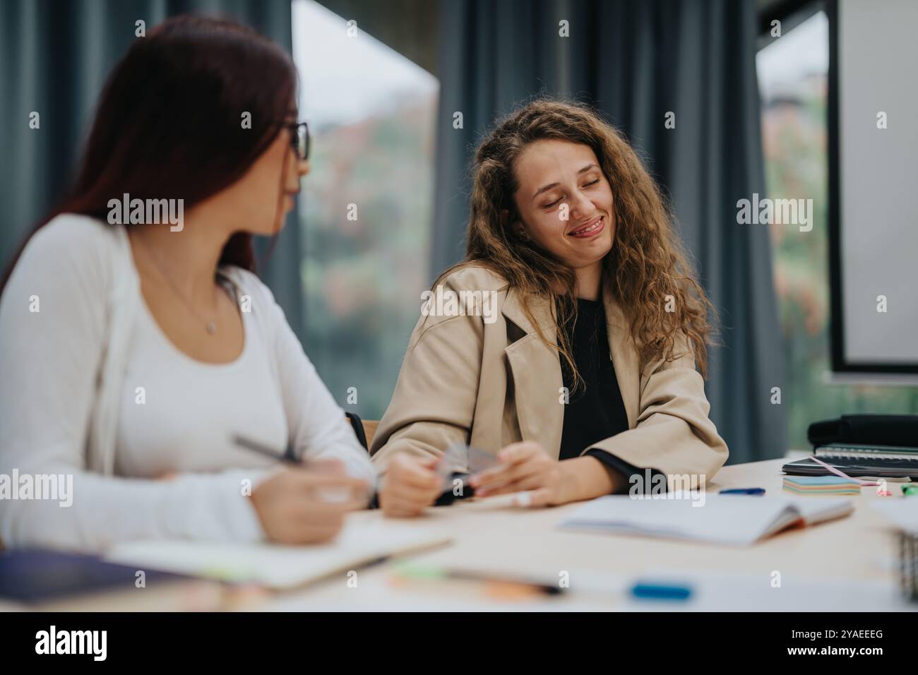 Two young women engaged in collaborative studying in a classroom Stock Photo - Alamy
