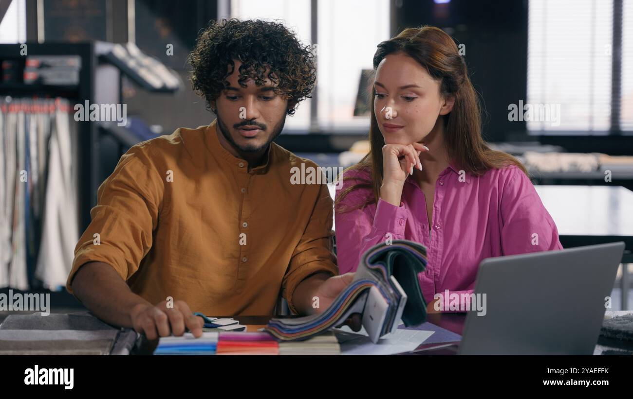 Female designer helping male client choose fabric material showing ...