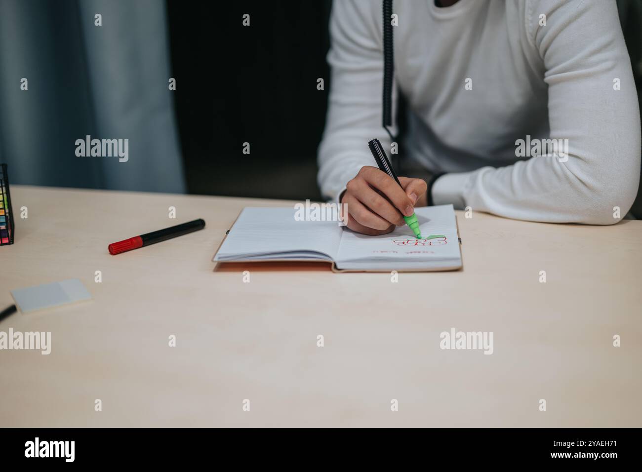 Student highlighting notes in a classroom setting Stock Photo - Alamy