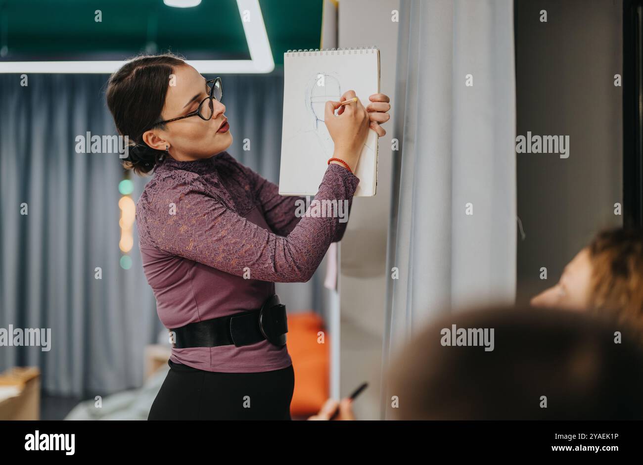Teacher demonstrating drawing technique to engaged students in ...