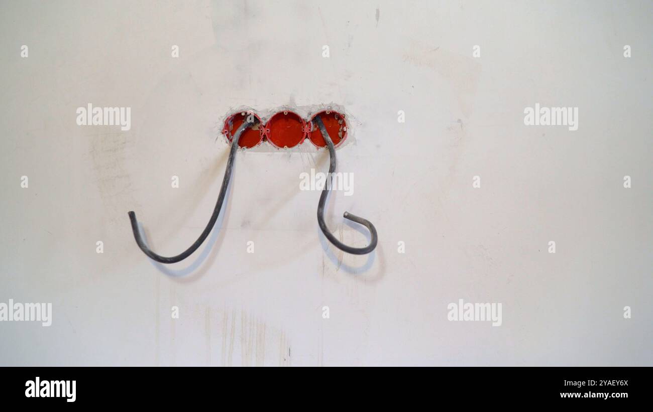 Electrician installing electrical sockets in wall using insulated wires ...