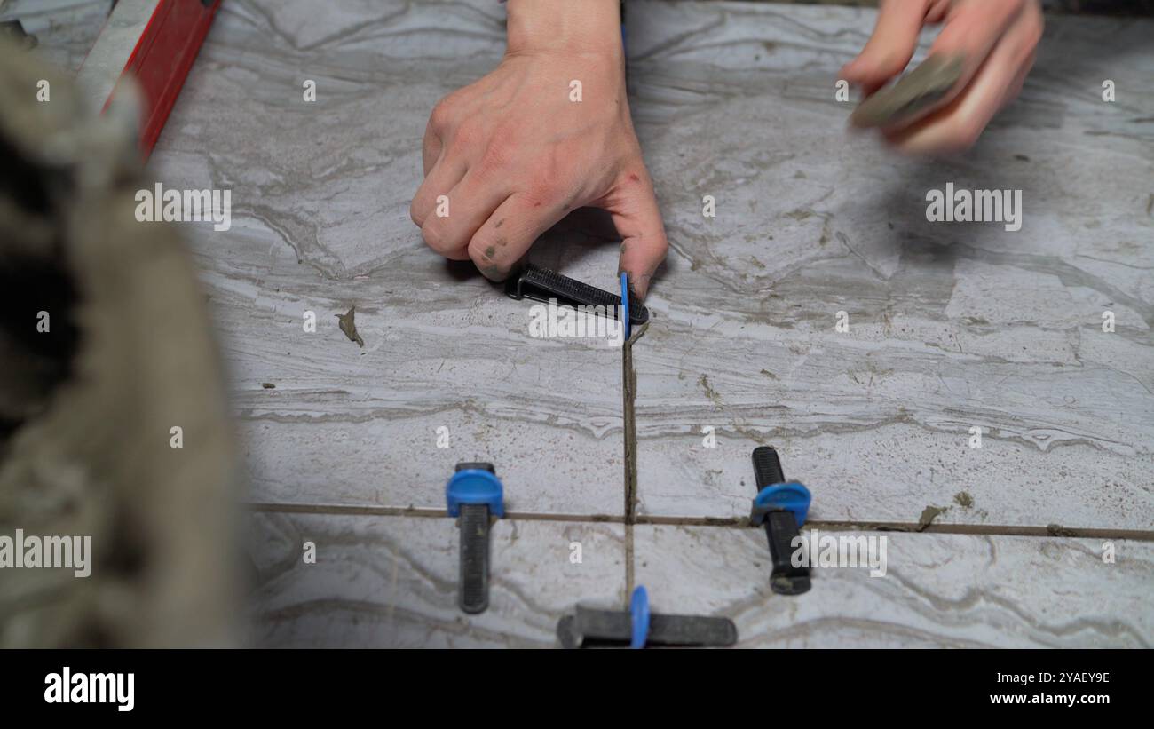 Construction worker placing tile leveling system clips during ...