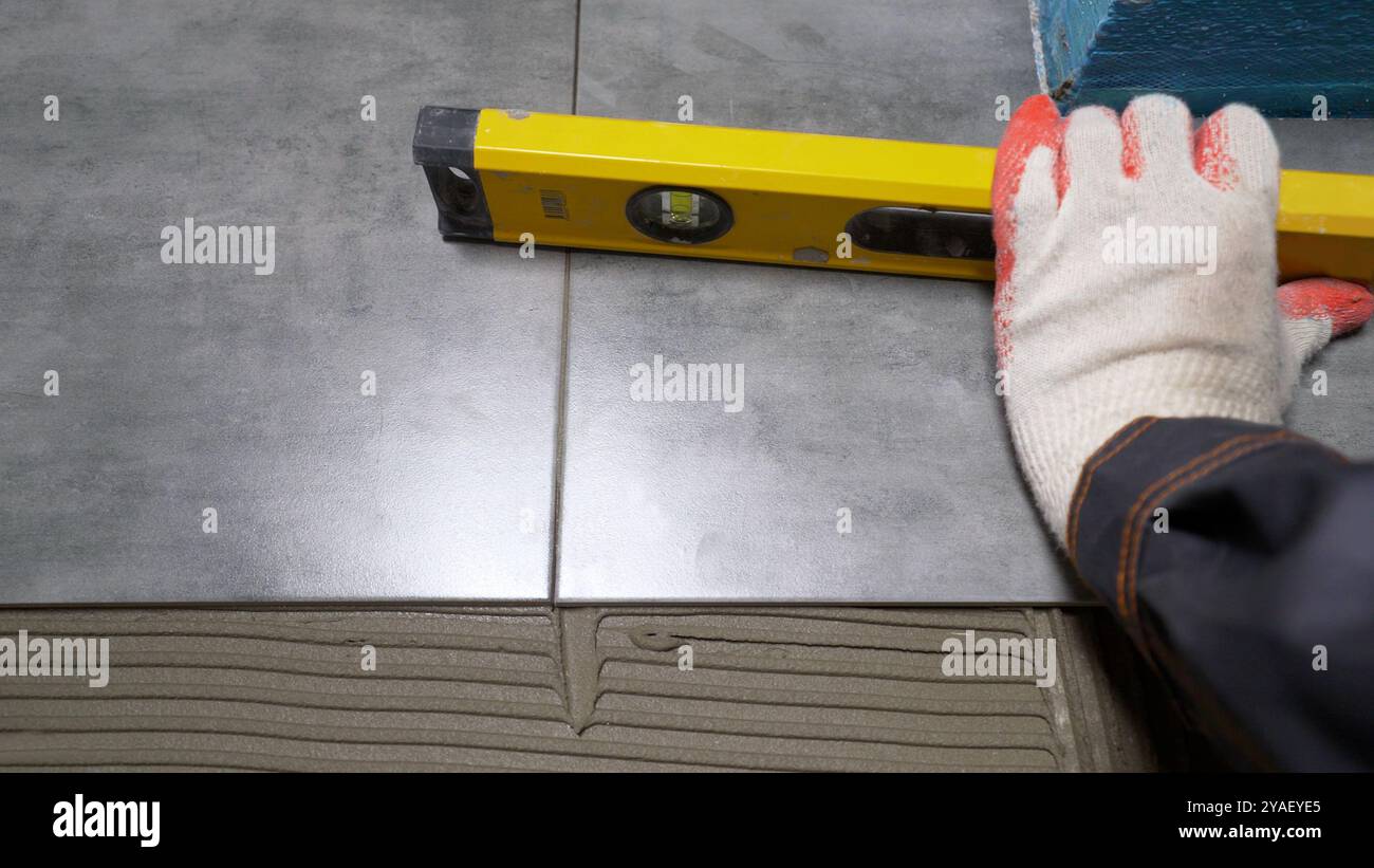 Construction worker leveling floor tiles using spirit level Stock Photo ...