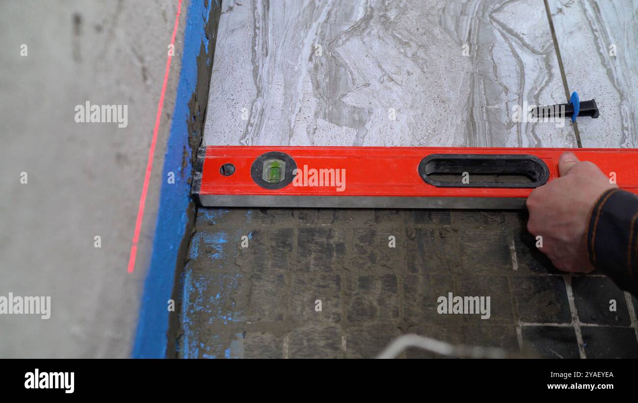 Construction worker using spirit level while laying tile Stock Photo ...