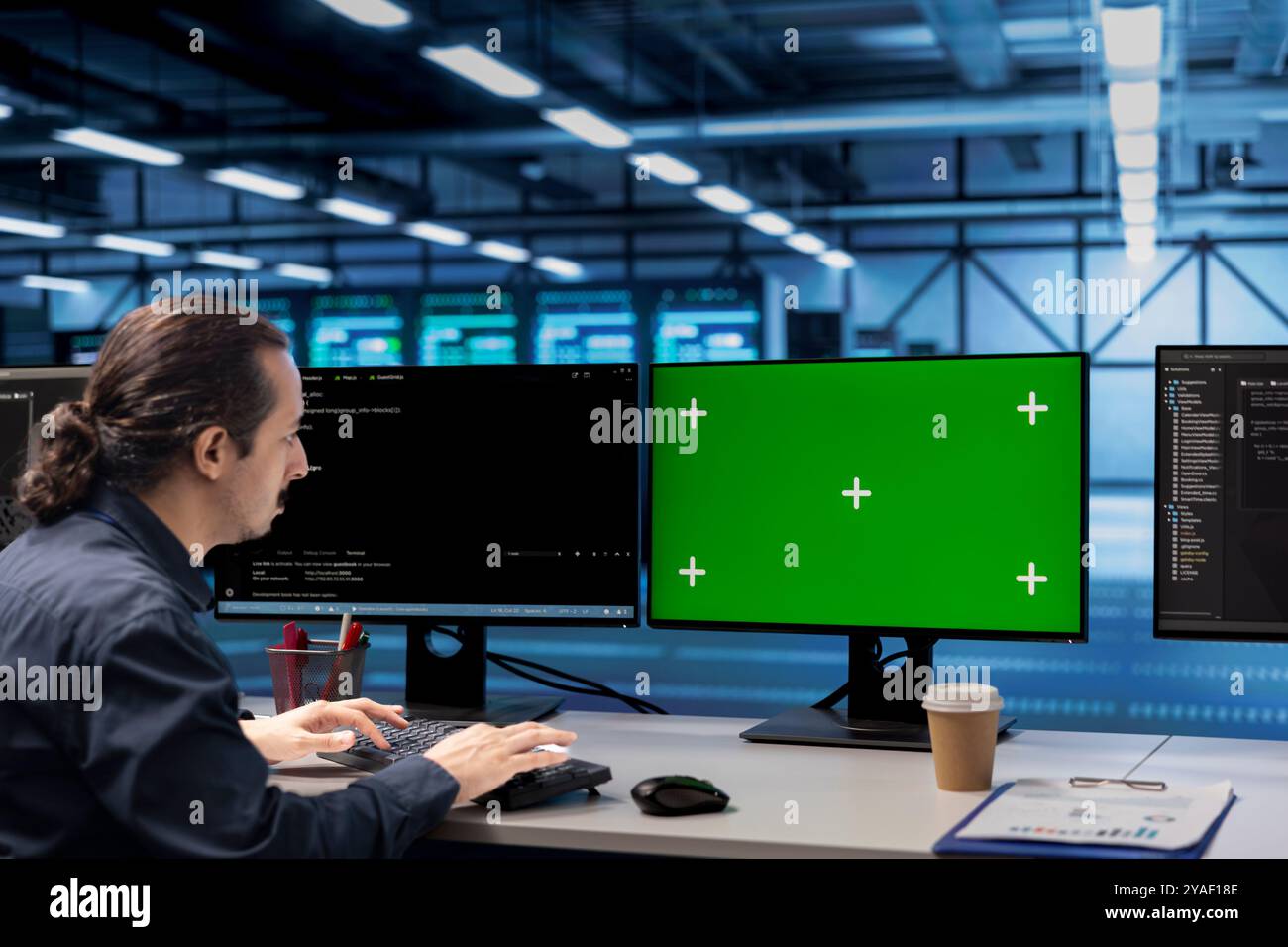 Admin in data center using diagnostic tools and system monitoring software on green screen PC to ...