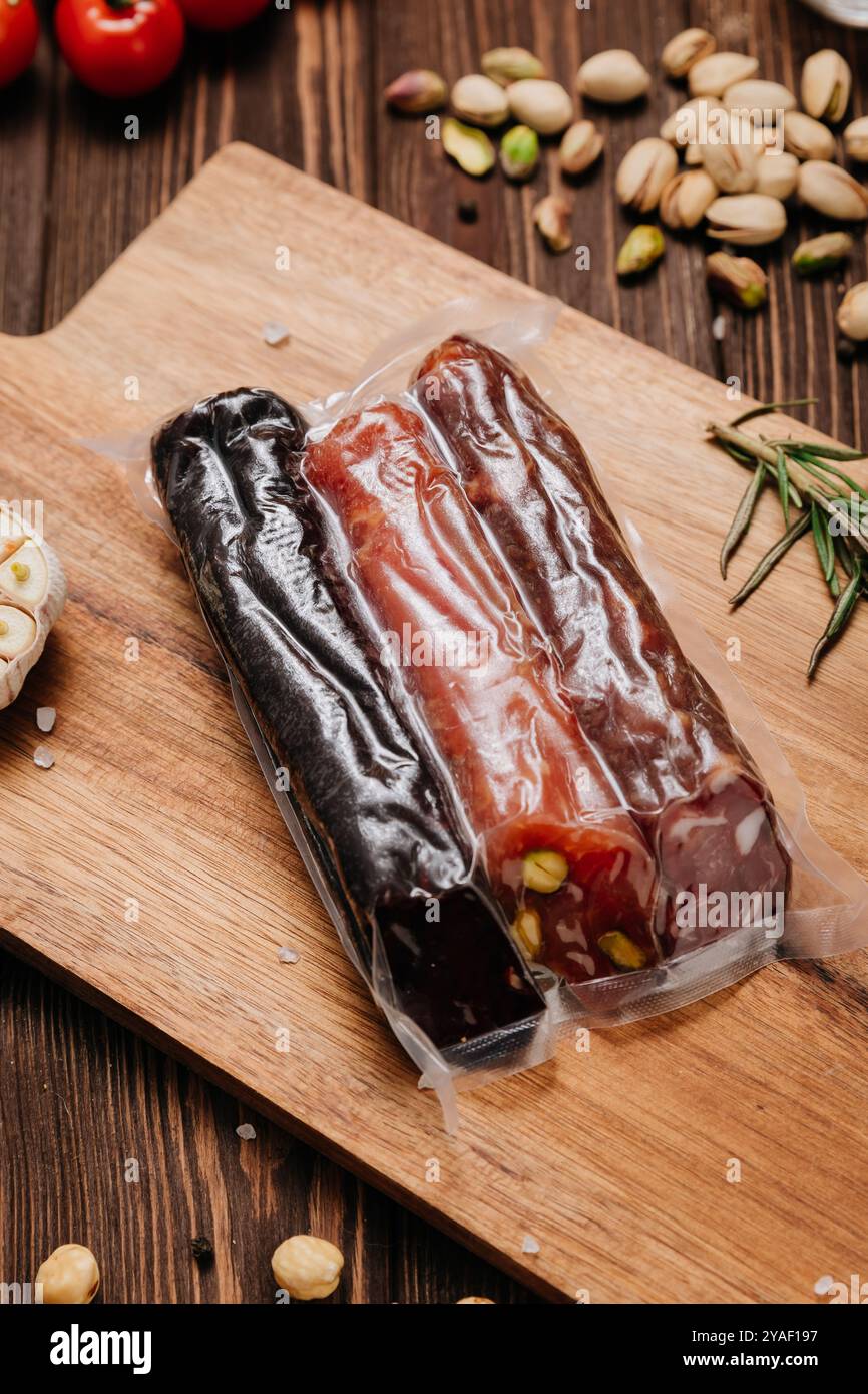 Assorted vacuum-packed salami with nuts and spices on board ...