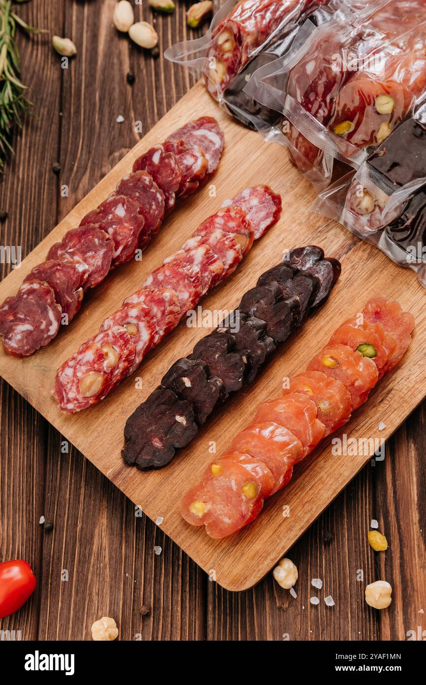 Assorted gourmet salami slices with nuts and spices on board ...
