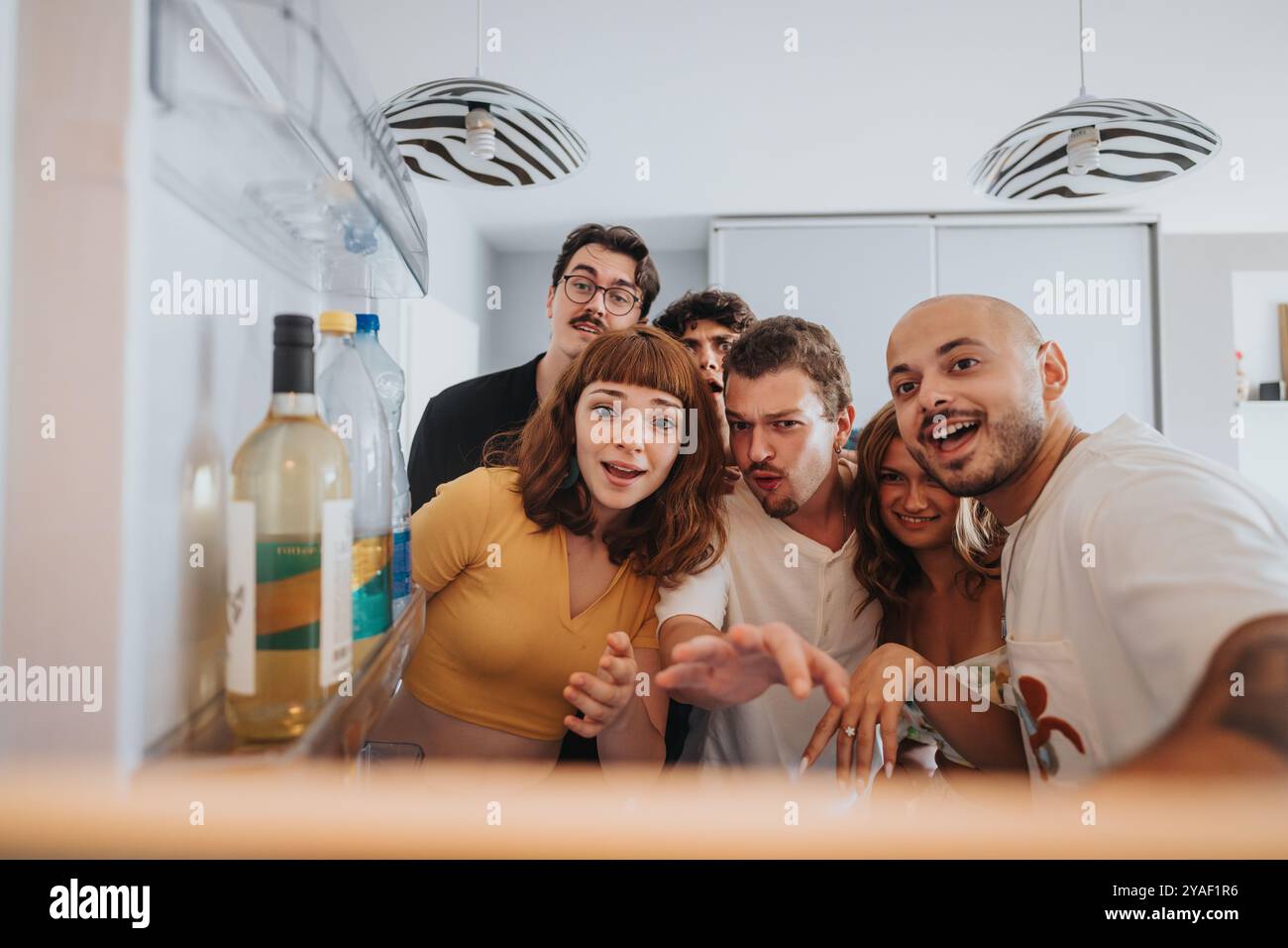 Group of friends exploring the contents of a refrigerator Stock Photo ...