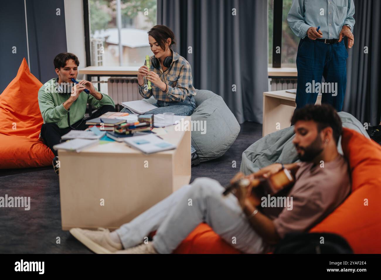 Music students practicing with instruments in a casual classroom ...
