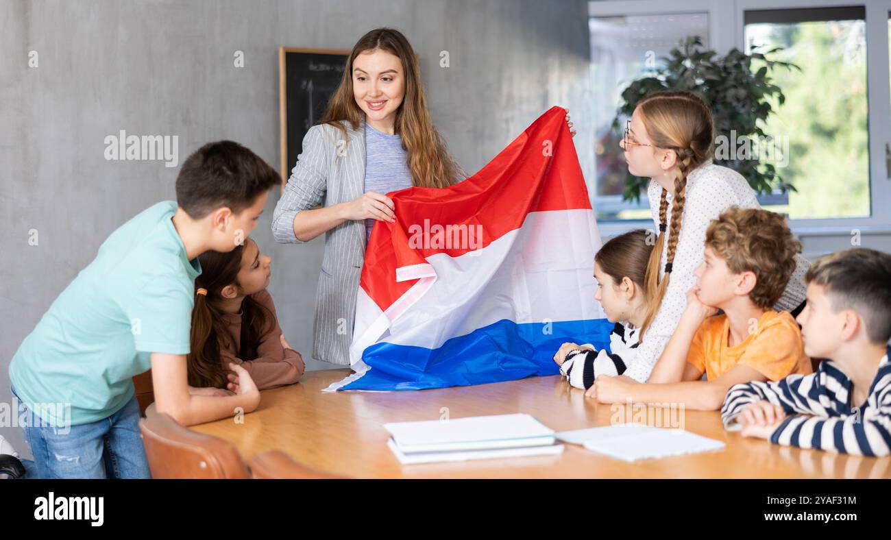 Preteens pupils looking at national flag of Netherlands while learning ...