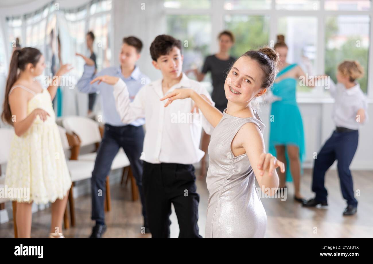 Teen girl in elegant evening dress dances incendiary twist with boy ...