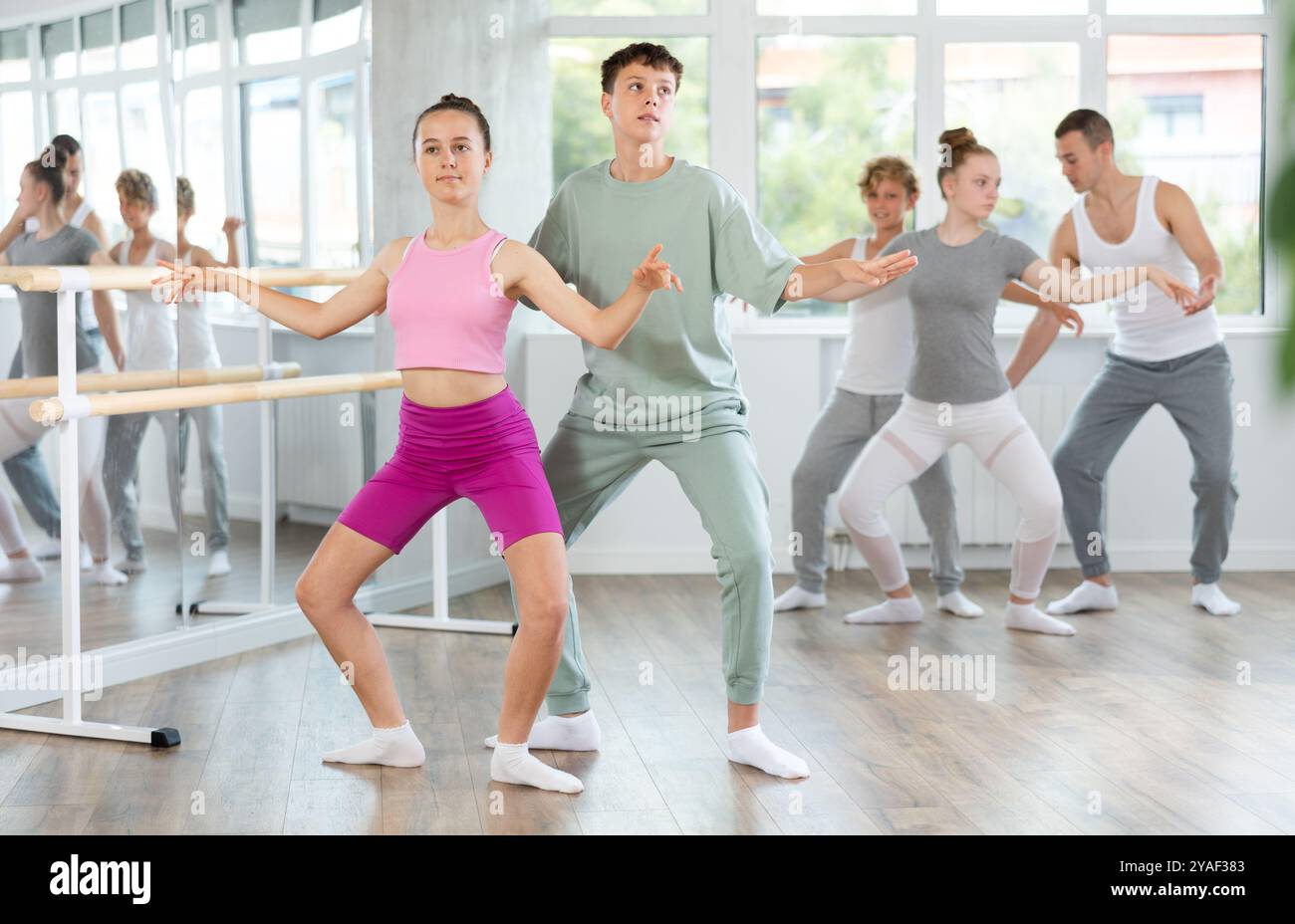 Teenage girl and boy practicing plie position of ballet in dance studio ...