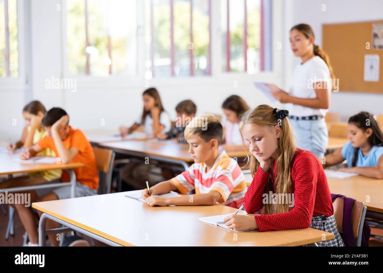 Preteen pupils studying in classroom with female teacher Stock Photo ...