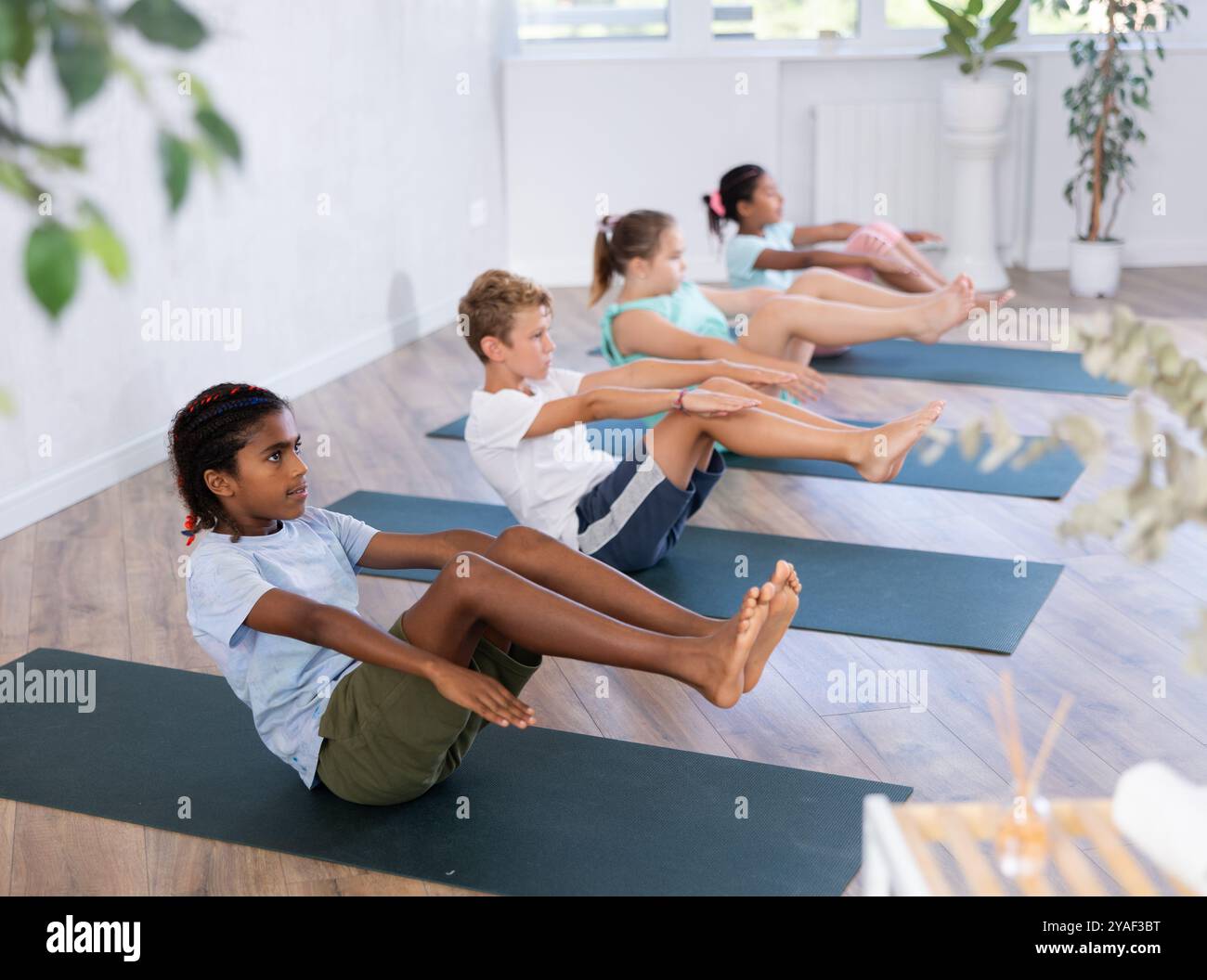 Girls and boys doing abdominal crunches with outstretched arms to ...