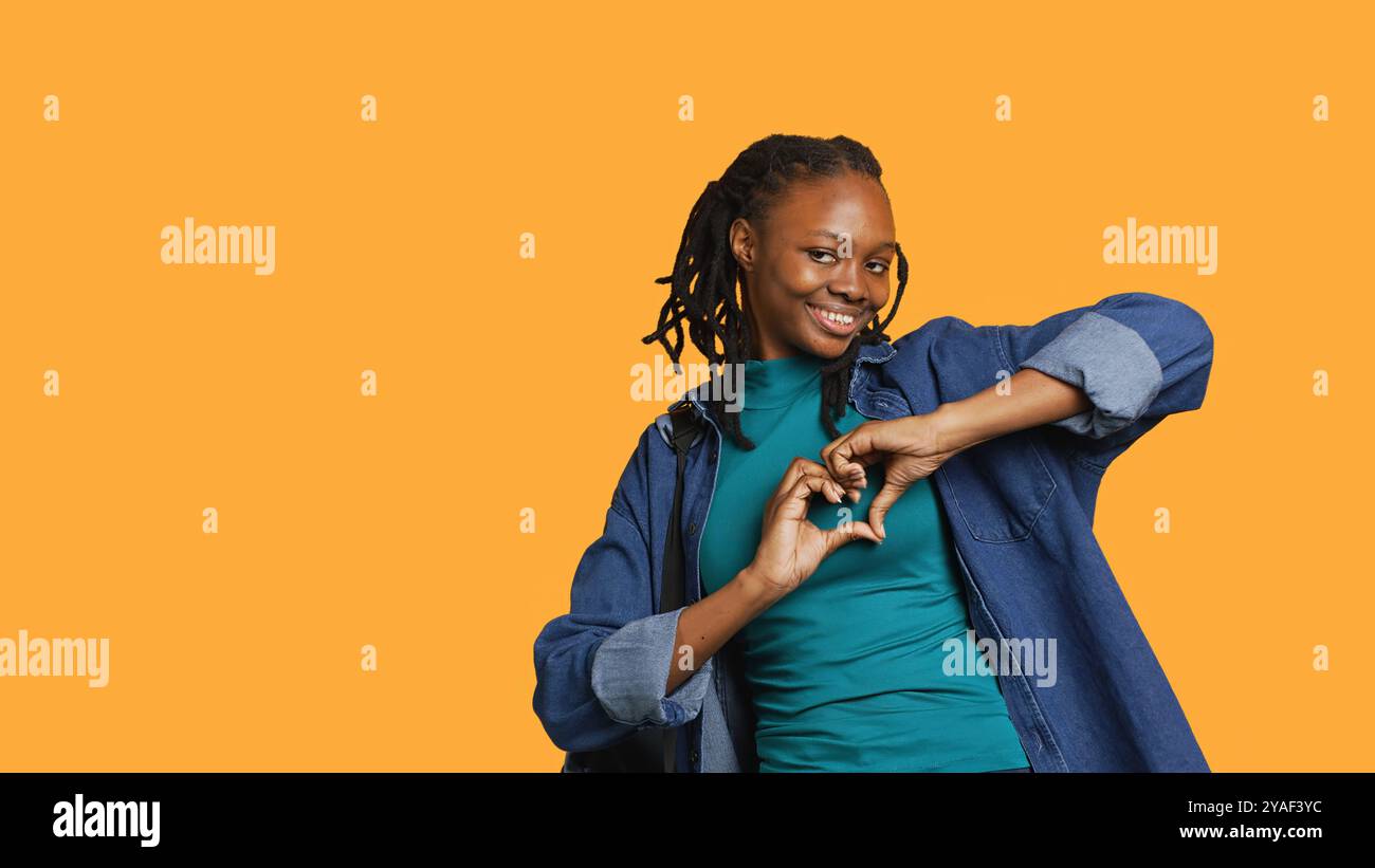 Portrait of friendly smiling african american woman doing heart symbol ...