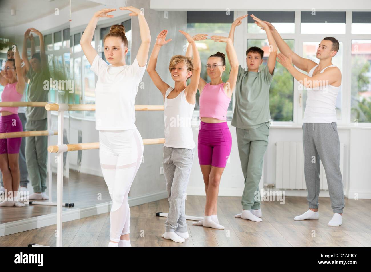 Girls and boys in ballet class perform fifth position under male ...