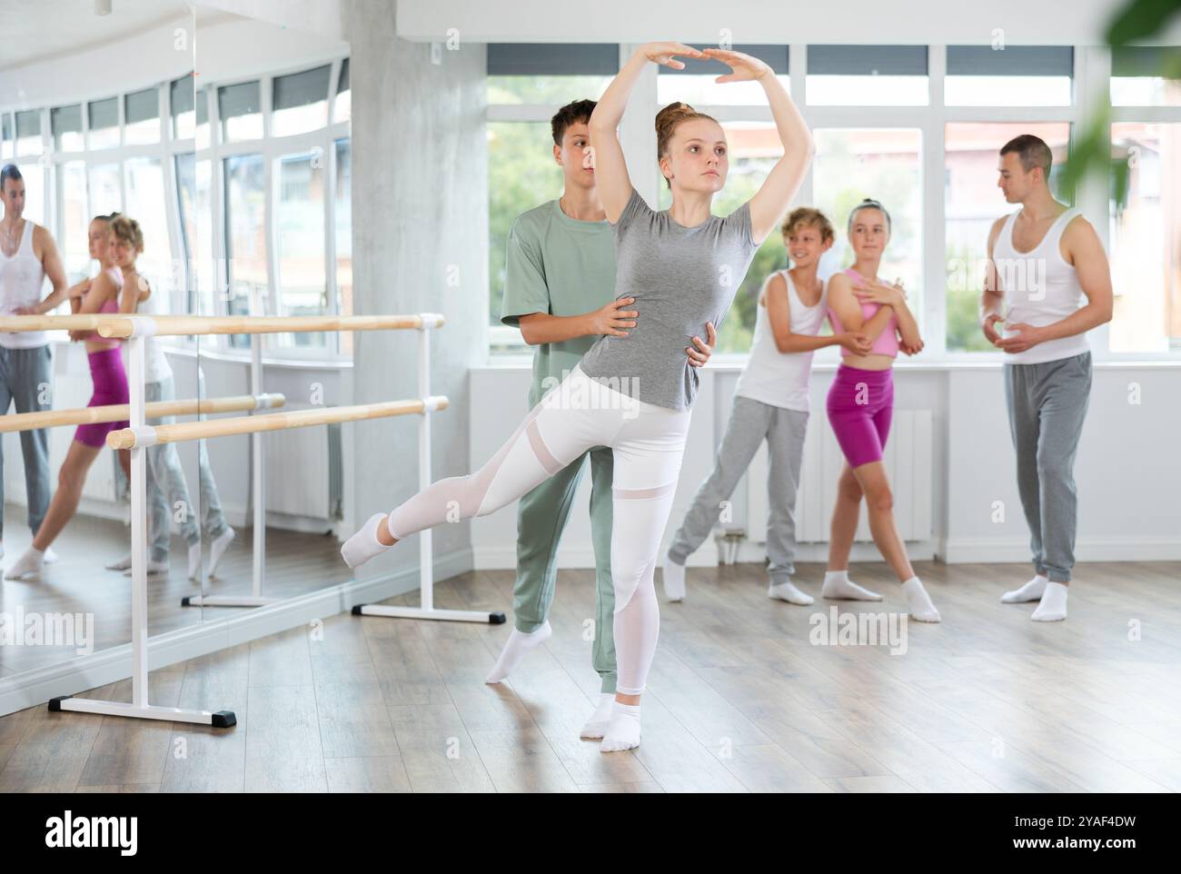 Teenage girl and boy practicing arabesque position of ballet in dance ...