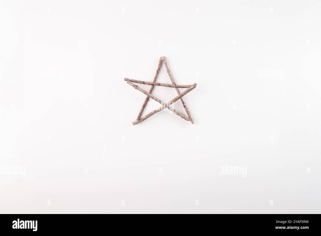 Five pointed star shape made from five small sticks on plain light ...