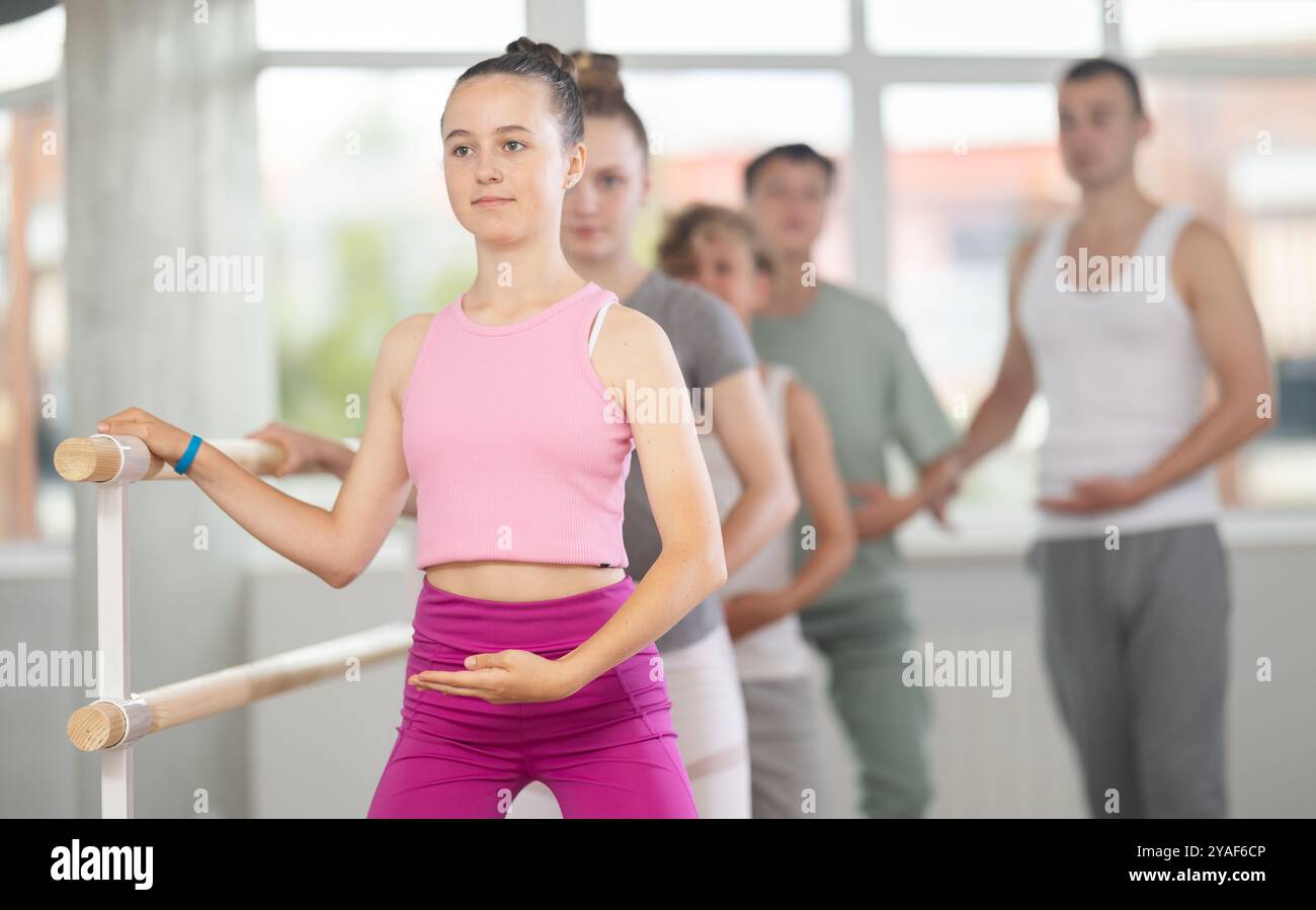 Teenagers doing ballet at group training session in the studio performs ...