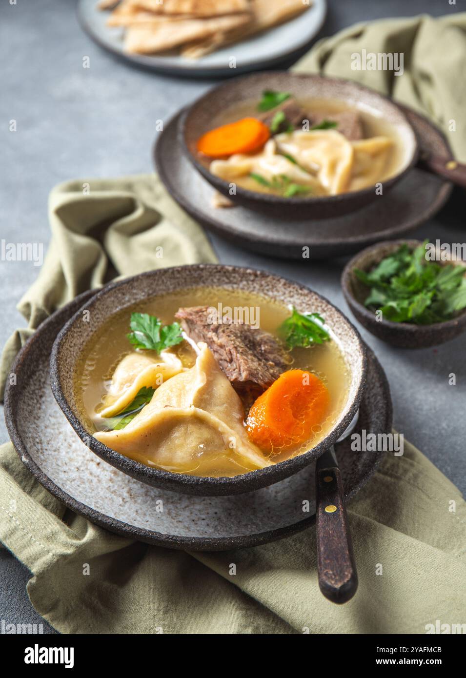 Traditional Jewish Kreplach soup with meat and carrot, gray background ...