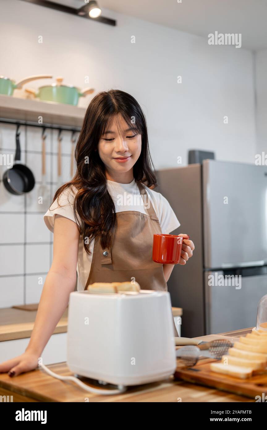 A portrait of a beautiful young Asian woman preparing her breakfast in ...