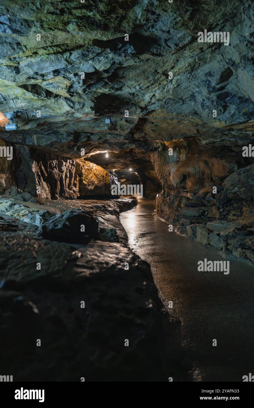 Dark cave made of rocks with water and artificial lighting, mysterious ...