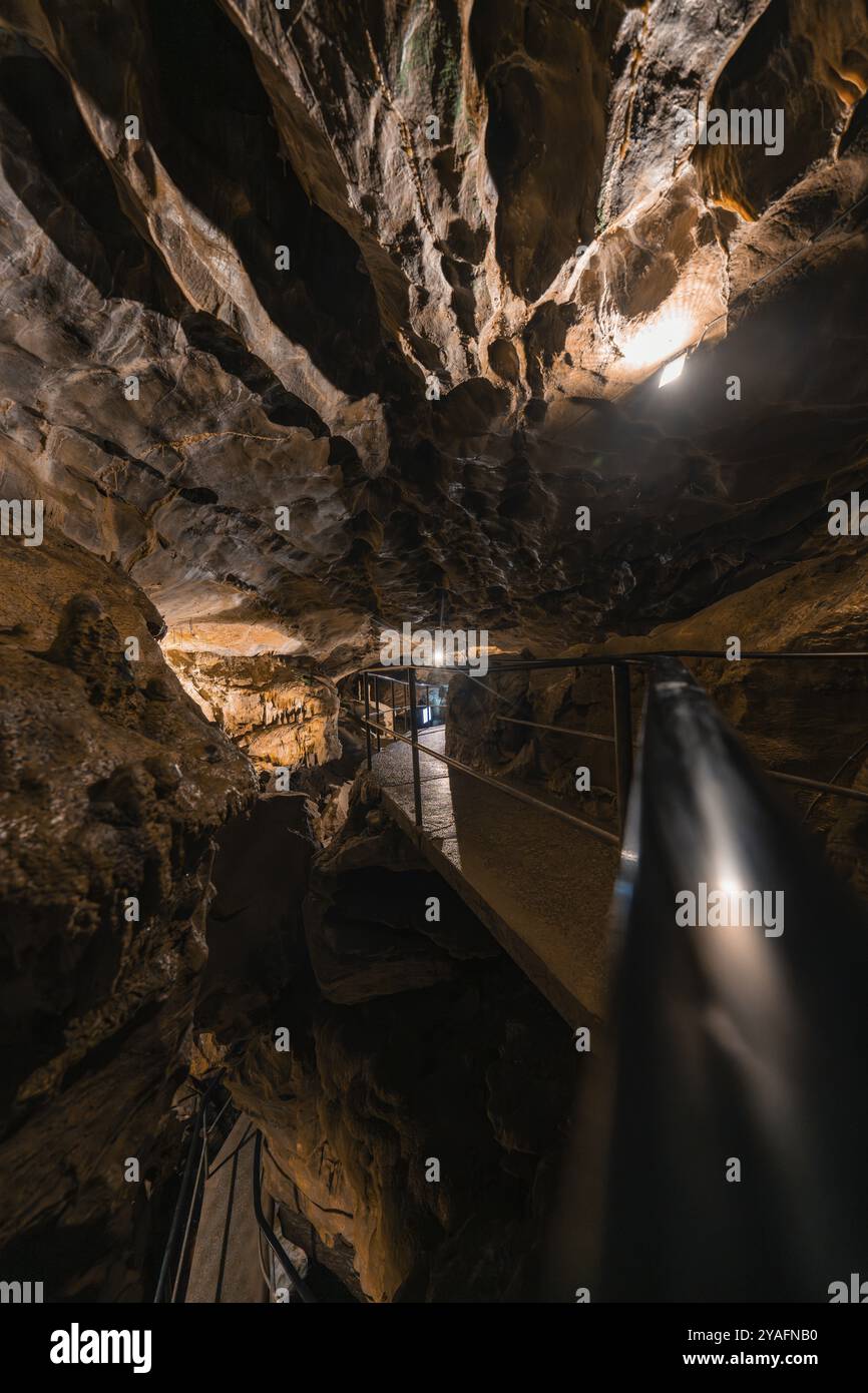 Illuminated path in a cave, surrounded by rocks and darkness ...