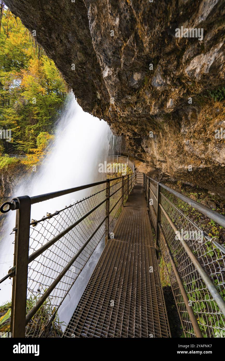 A hiking trail with metal railings leads along a waterfall under a ...