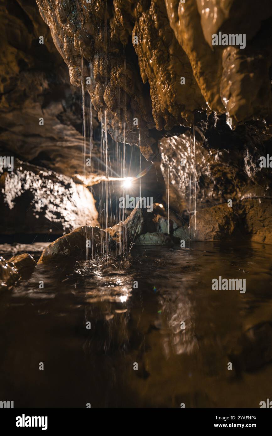 An illuminated cave room with dripping water and fascinating formations ...