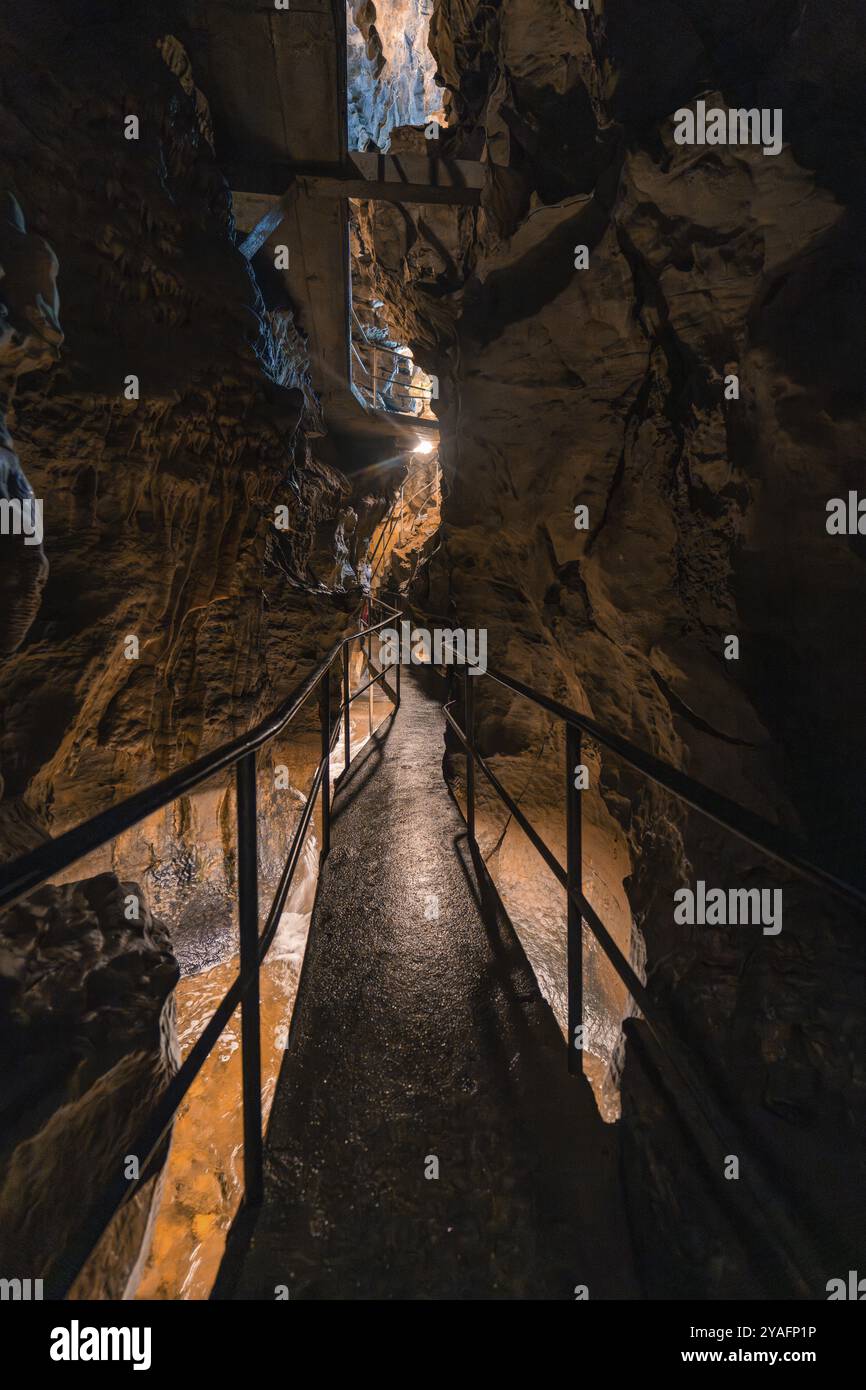 Narrow path through a cave, illuminated, surrounded by rocks and an ...