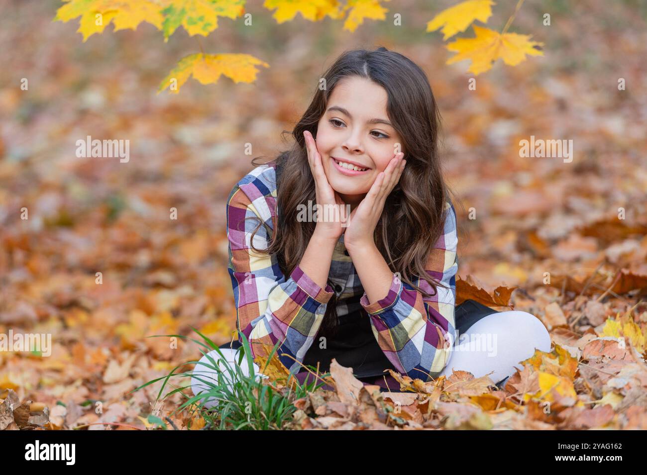 Autumn girl in school uniform sit in fall leaves outdoor. Stylish teen ...