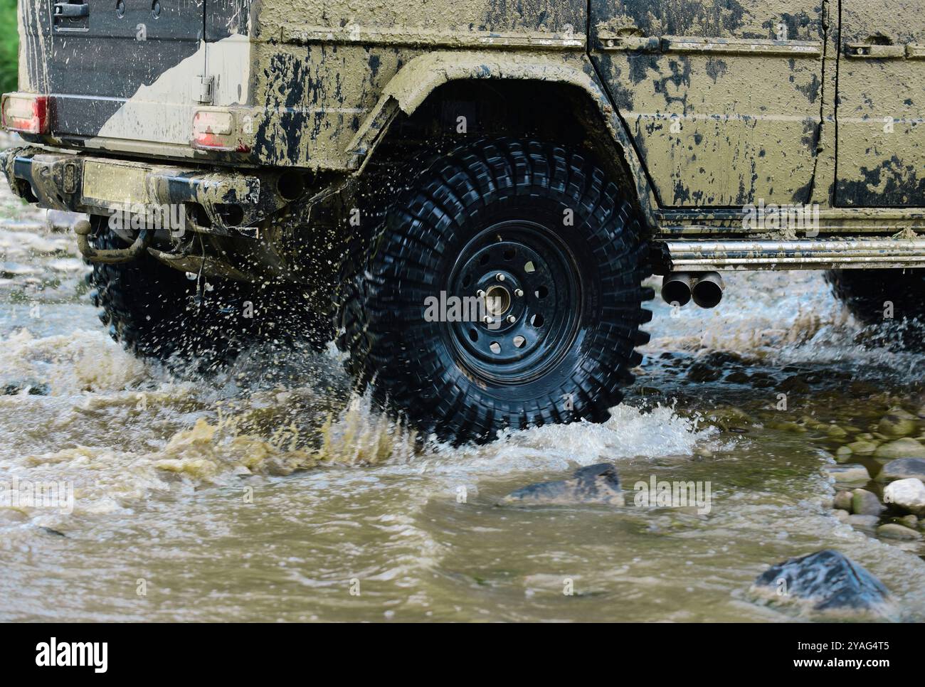 Off-road travel on mountain road. Bottom view to big offroad car wheel on country road and ...