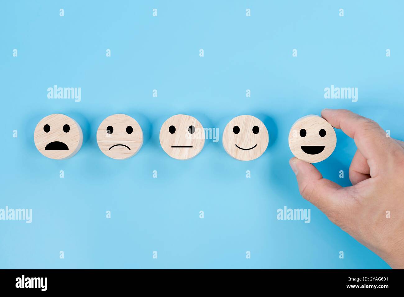 Hand holding smile face symbol on wooden cube blocks on blue background ...