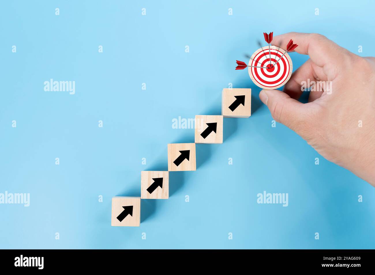 Man hand holding wooden block with target aiming dart board and arrow ...