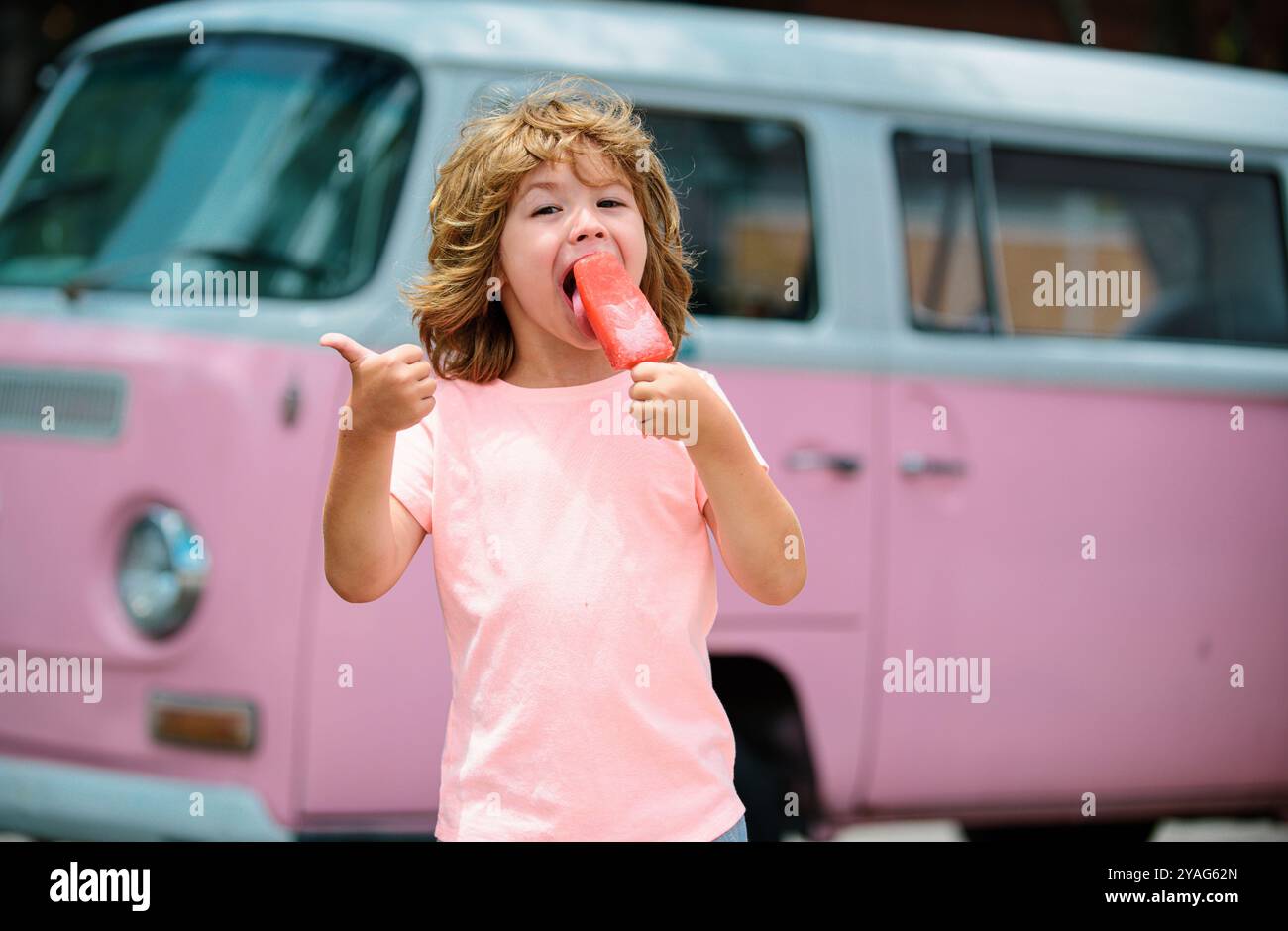 Child with frozen dessert in hand. Kid in a pink dress eating an ice ...