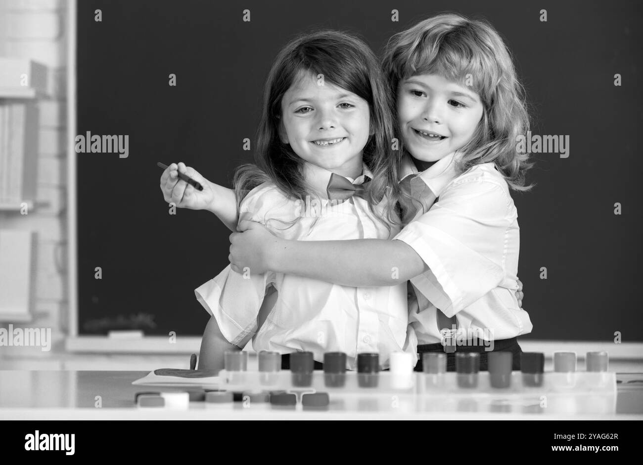 School children girl and boy hugging, painting with paints color and ...