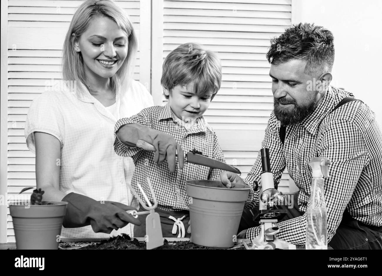 Cheerful three people with cute child growing plant in pot. Little cute ...