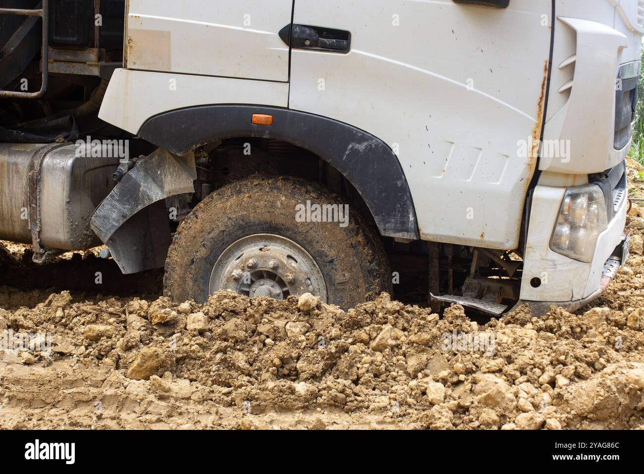 a stuck dump truck on a dirt road of a tropical island. Loose soil ...