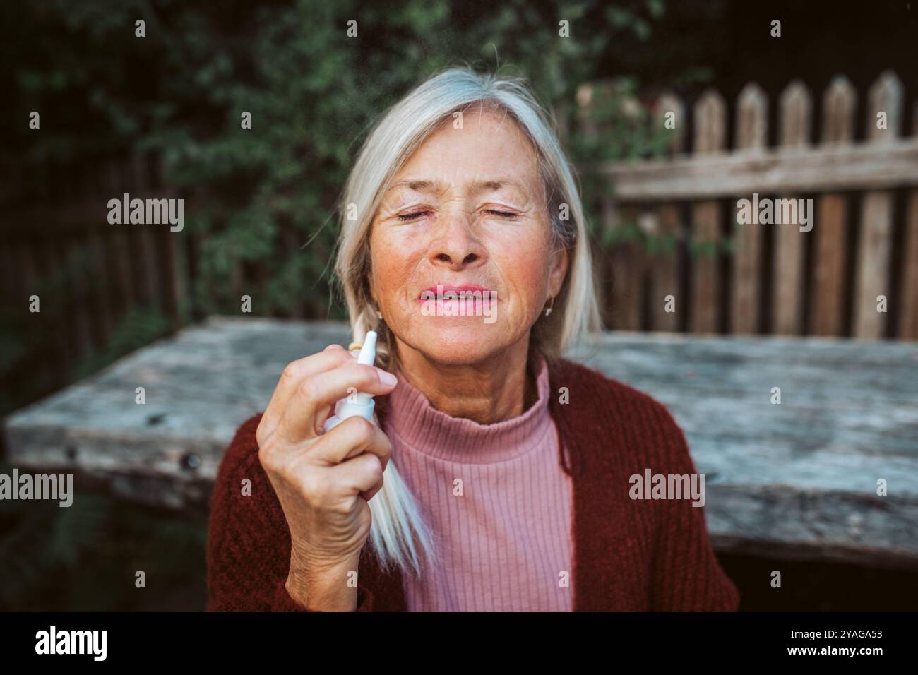 Senior woman feeling sick, using nasal spray to help with congestion ...