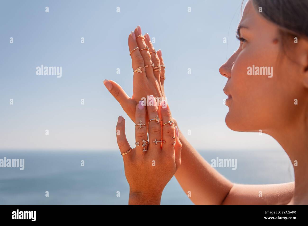 A woman is wearing many rings on her hands and is looking out at the ...