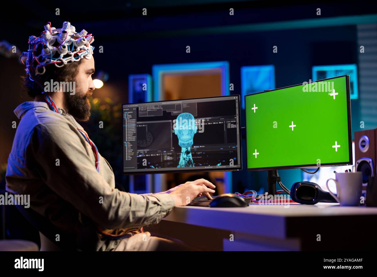 Man with EEG headset on writing code on green screen PC to transfer mind into virtual world ...
