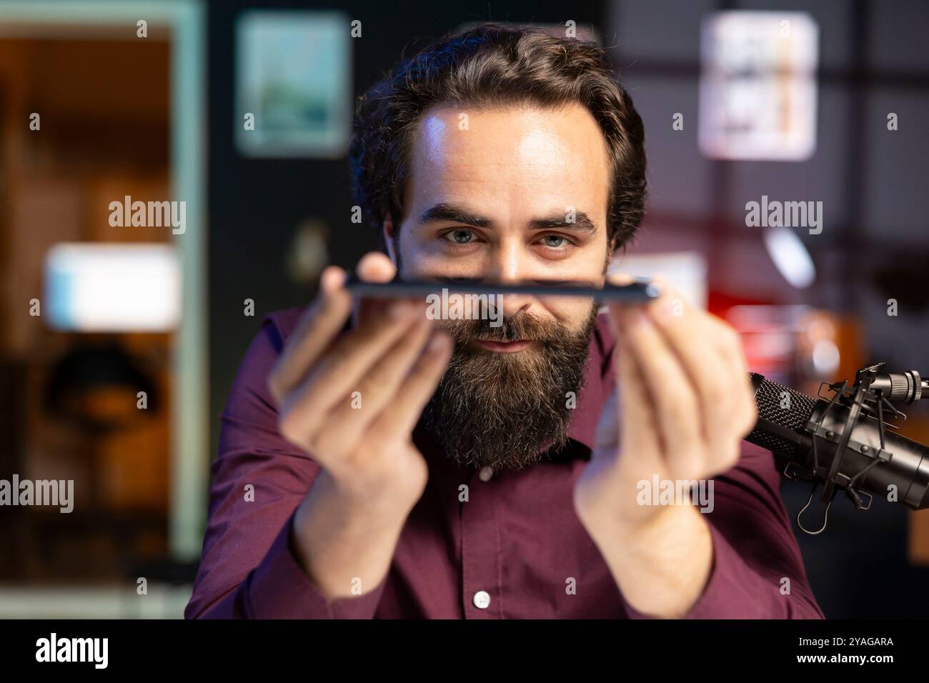 Tech guru reviewing latest phone, impressed by its thinness while ...