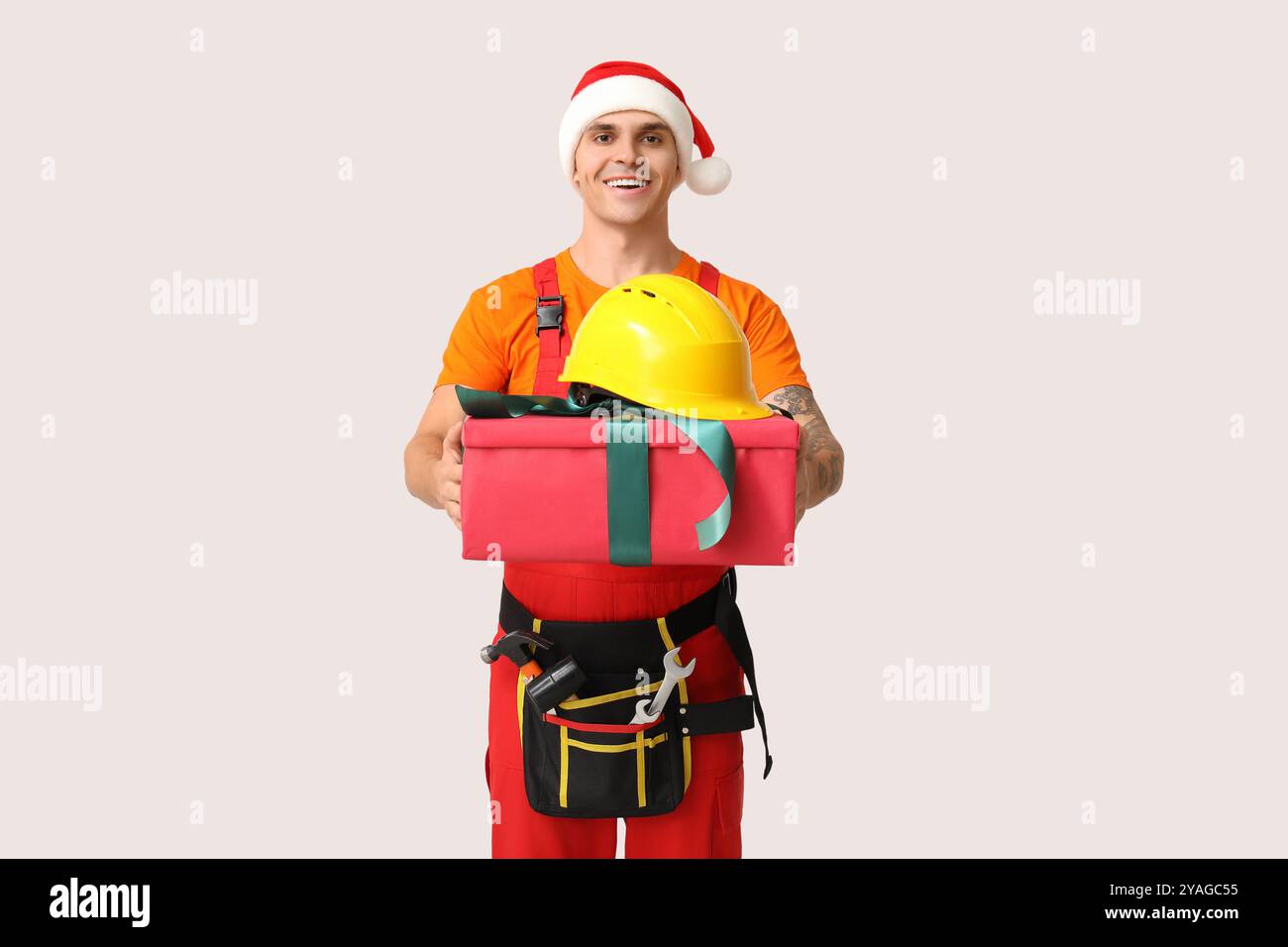 Handsome male builder in Santa hat with professional tools, gift box ...