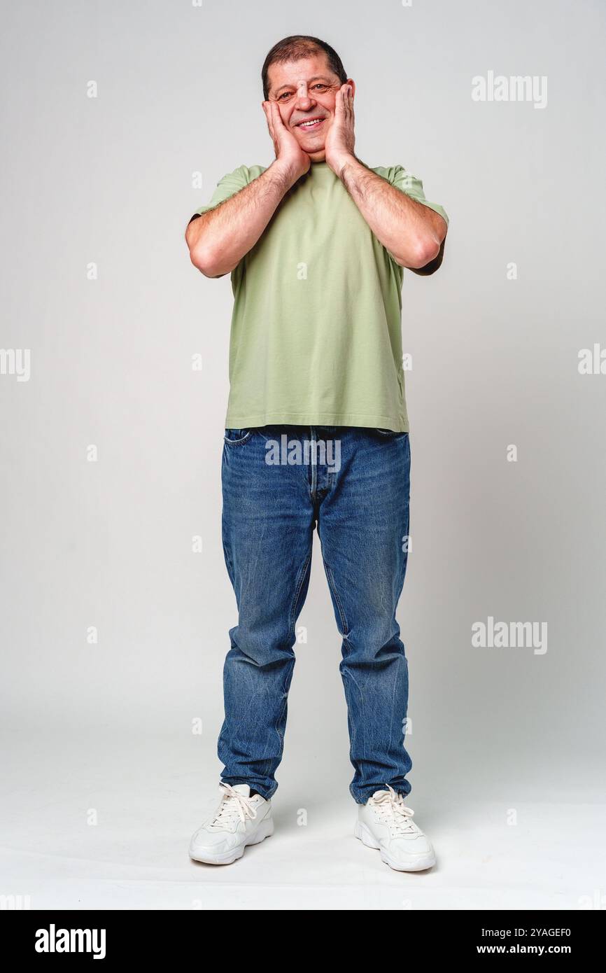 Happy middle-aged man showing joy while touching his face against a ...
