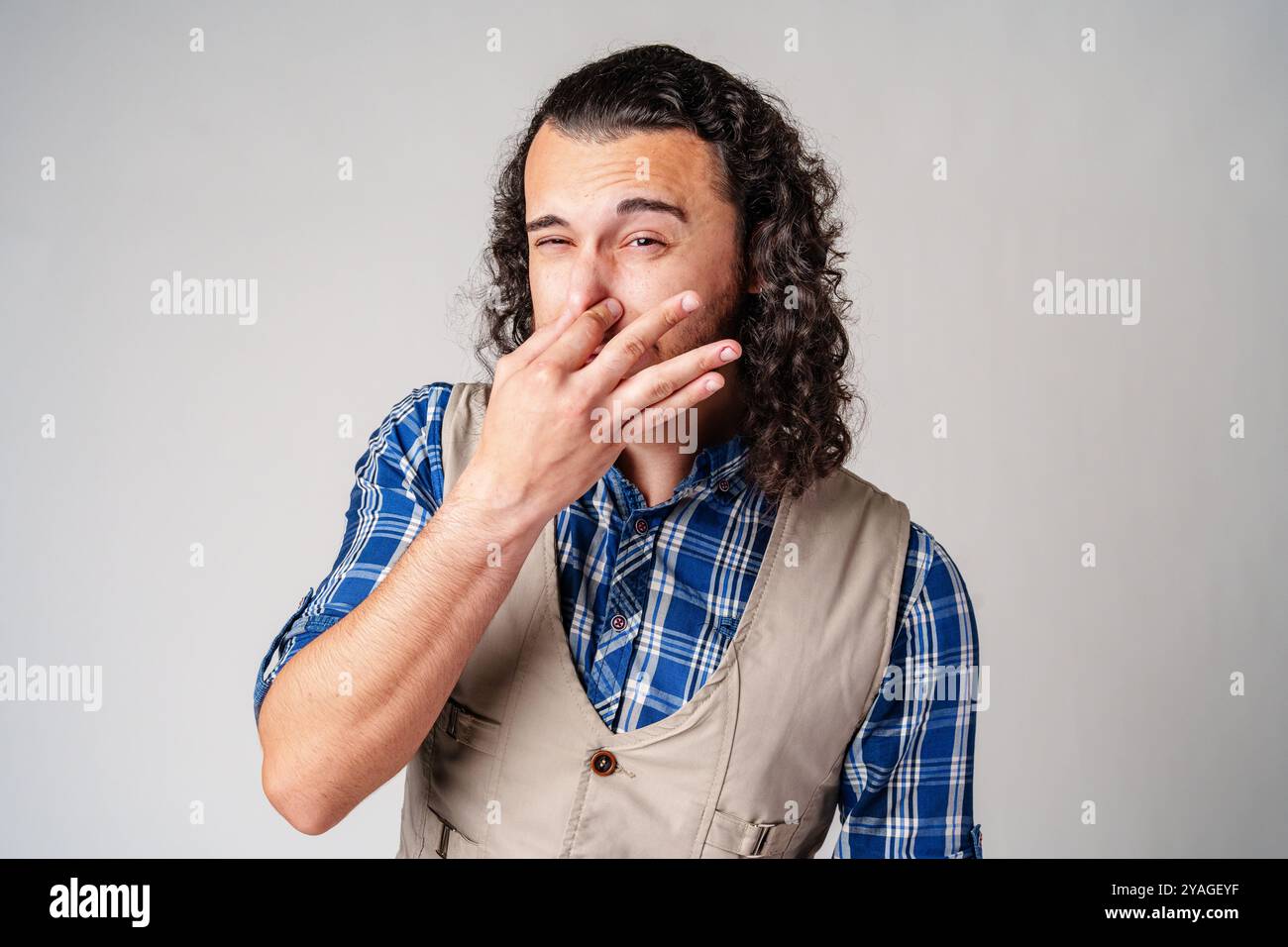 Man making a funny face while pinching his nose in a studio setting ...