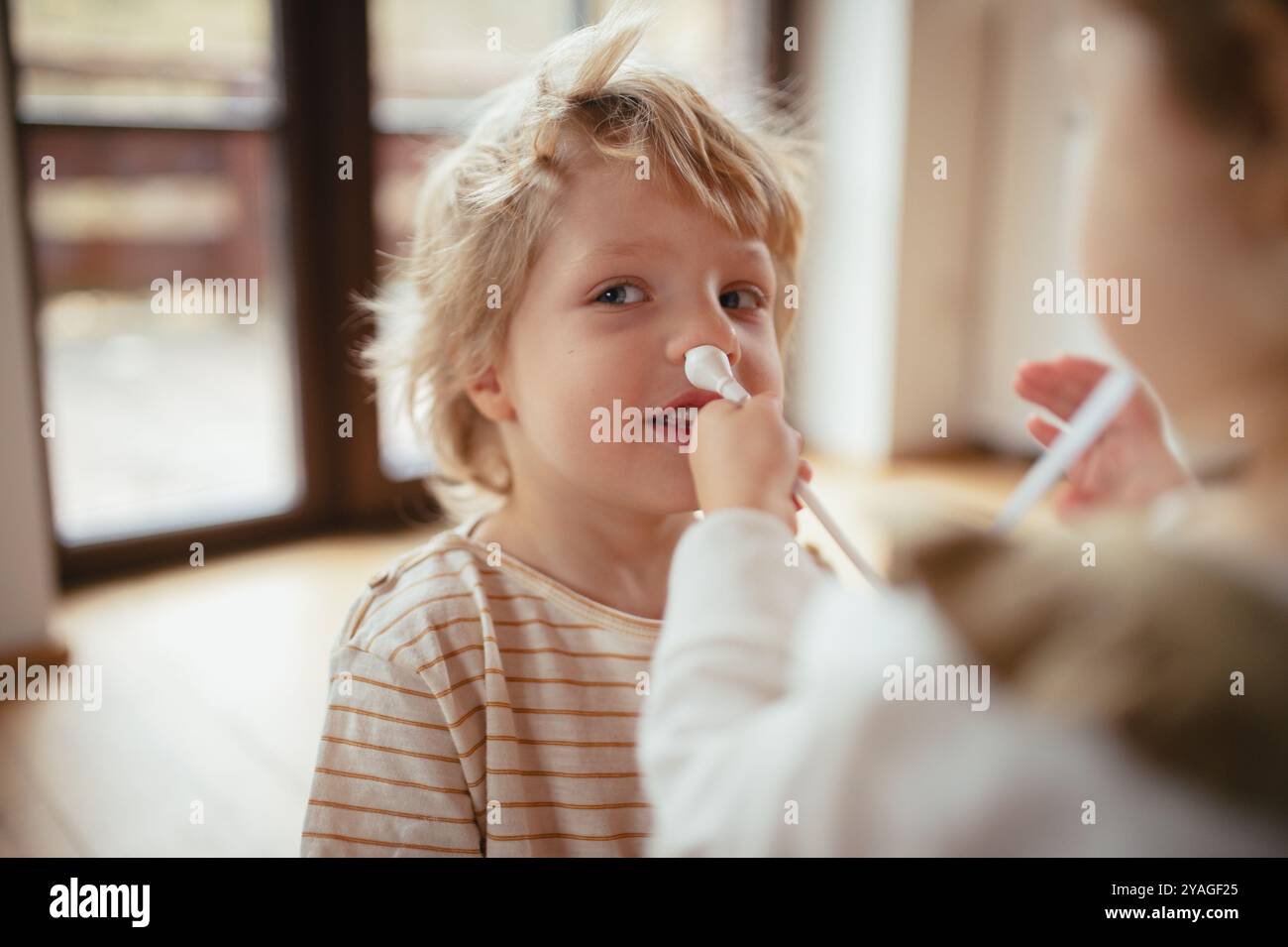 Boy with stuffy nose, using nasal suction bulb to clear mucus from his ...