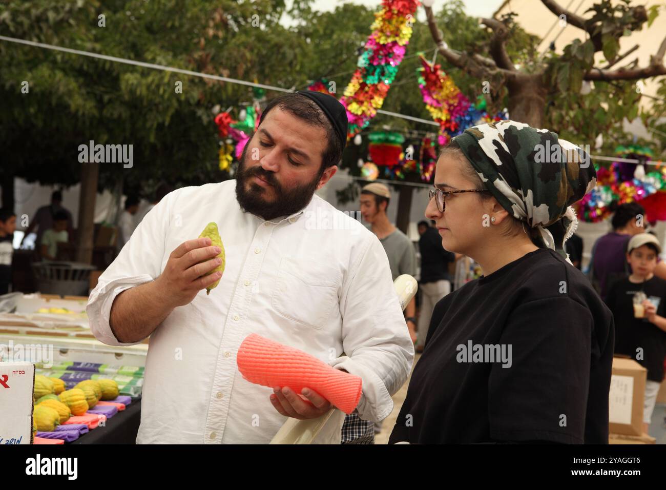 Orthodox Jewish man stand with his wife examining an Esrog, Etrog or ...