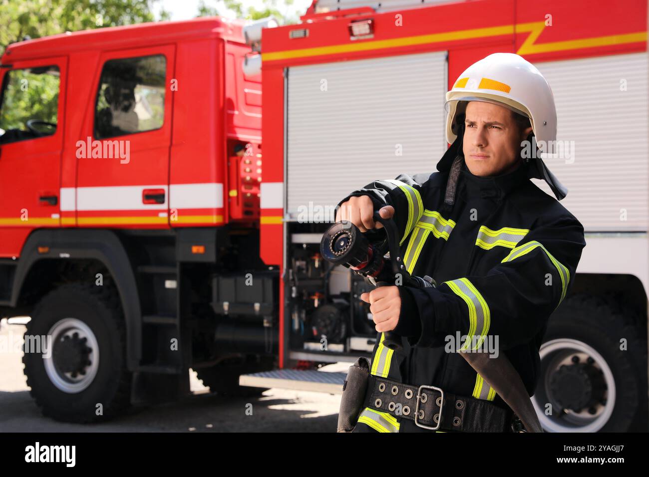Firefighter in uniform with high pressure water jet near fire truck ...